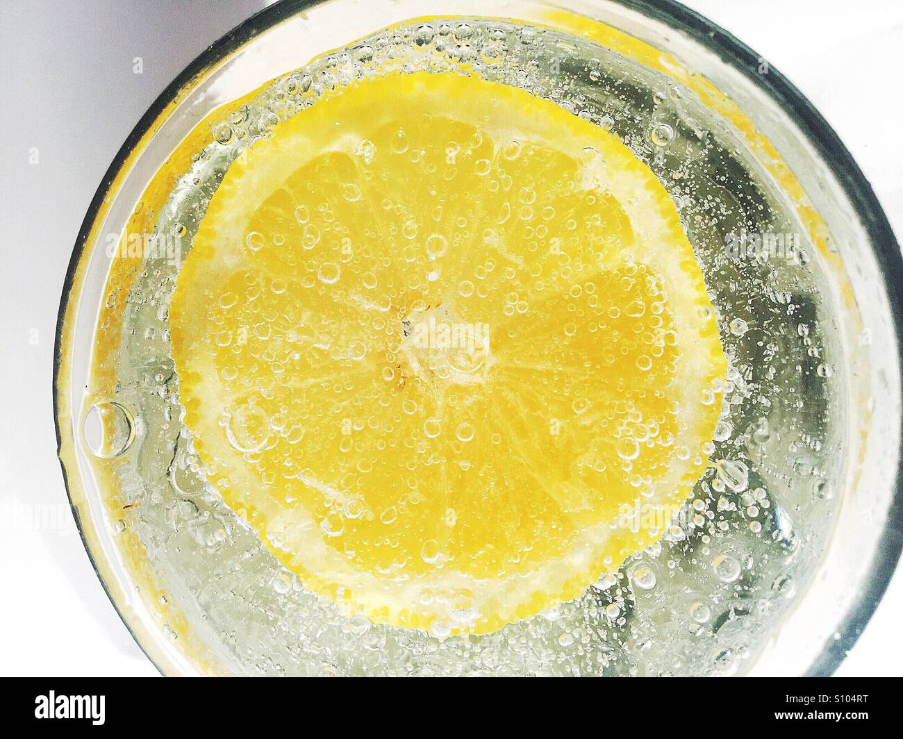 A slice of lemon floating in a glass of carbonated mineral water ...