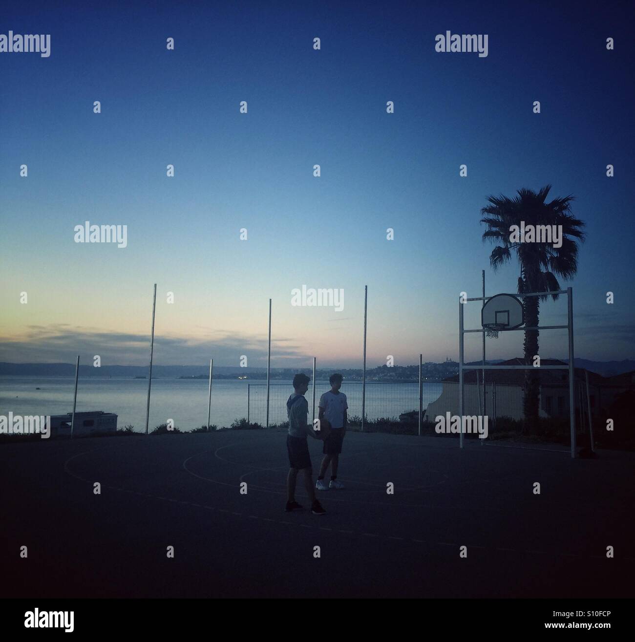 Young people playing basketball at sunset Stock Photo - Alamy