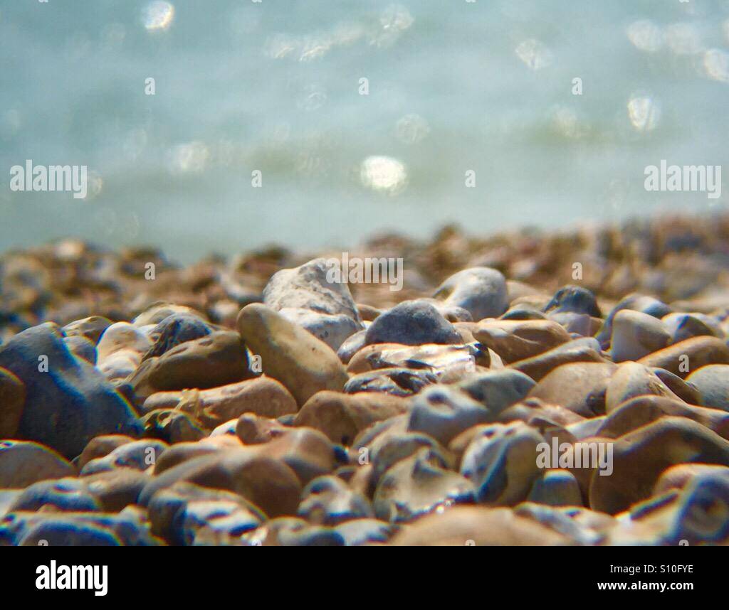 Shingle beach with shimmering sea in distance Stock Photo - Alamy