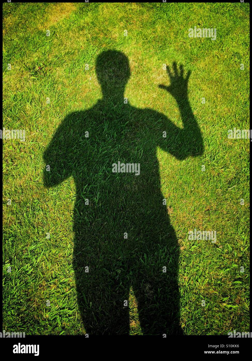 Shadow of a man with one arm raised and all fingers and thumb separated ...