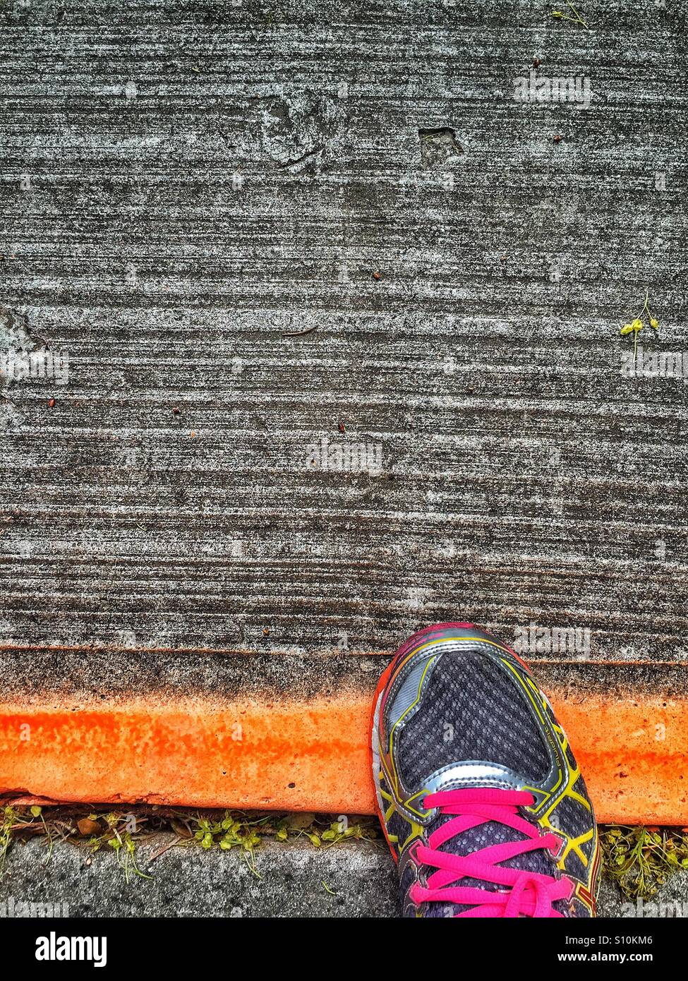 Tip of running shoe crossing neon orange line on sidewalk Stock Photo ...