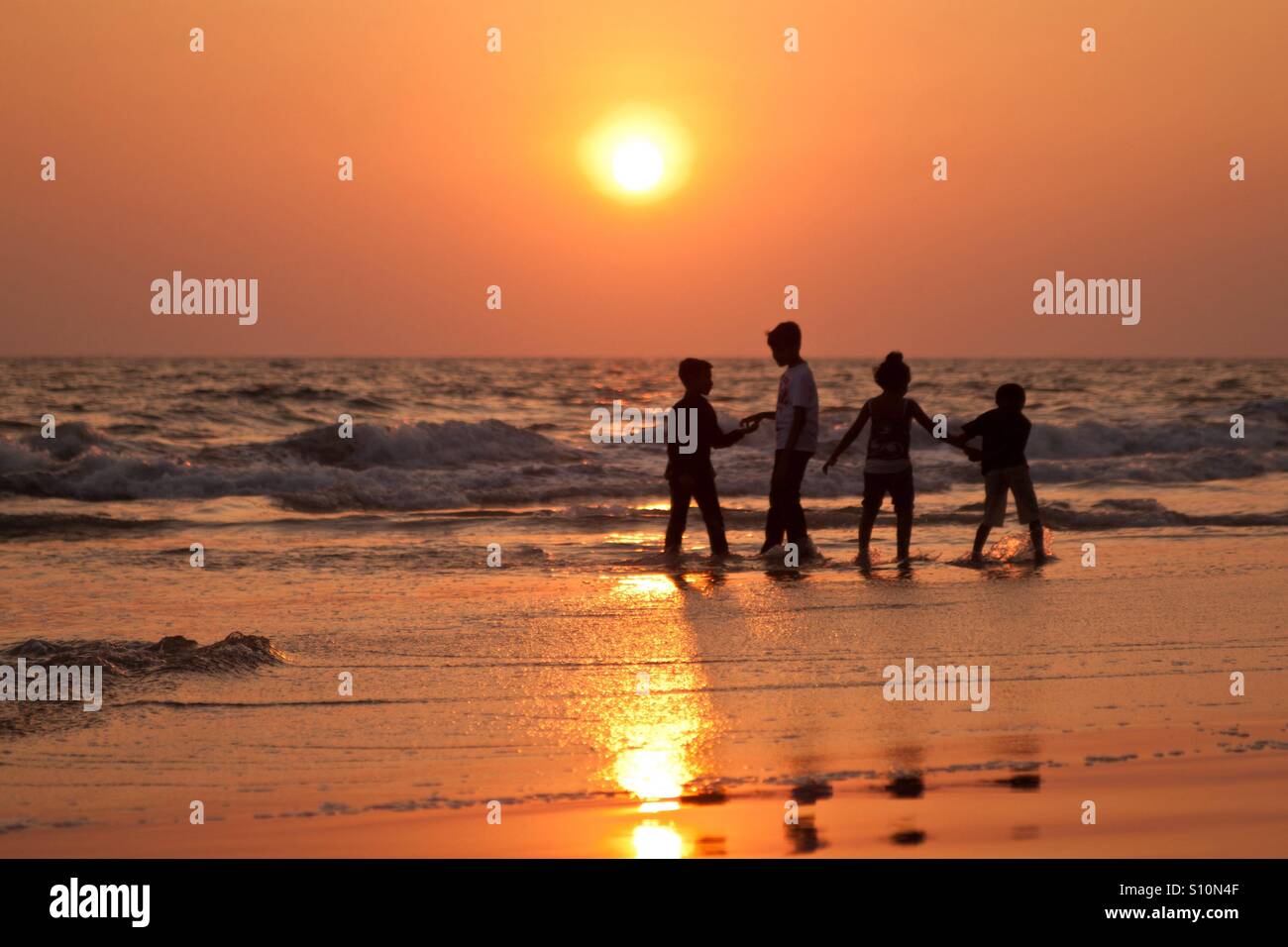 Kids playing on the beach during sunset Stock Photo - Alamy