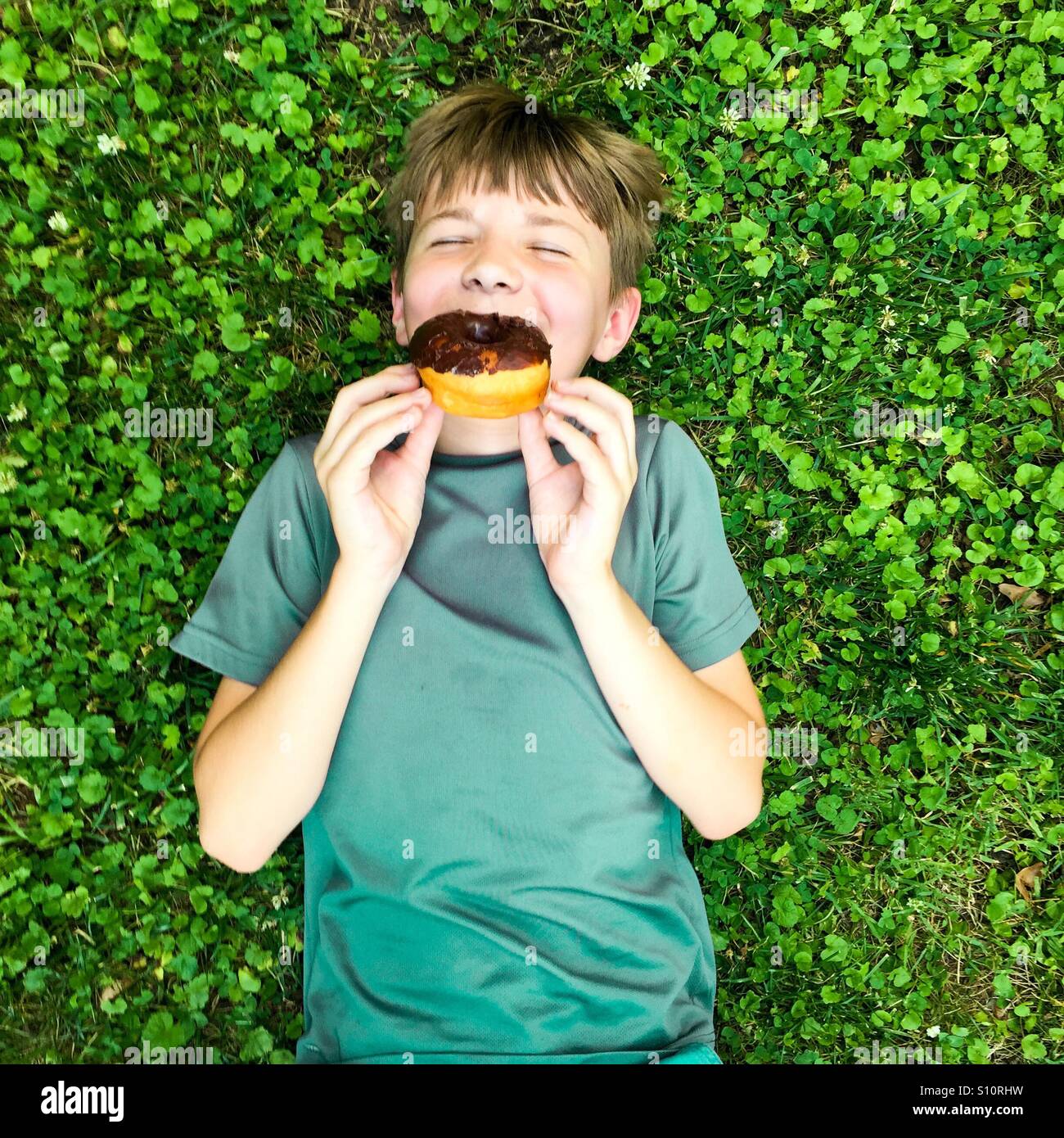 Boy eating a donut, doughnut in the park Stock Photo - Alamy
