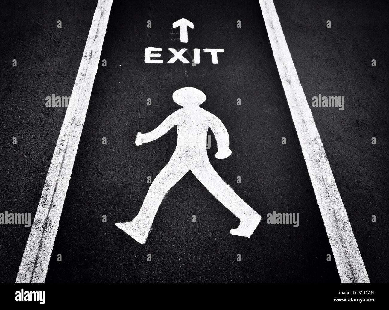 An exit sign showing a walking man painted on the concrete floor of a ...