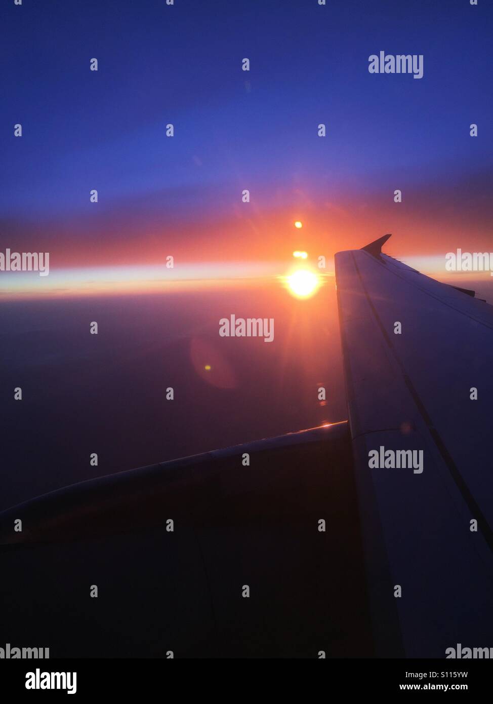 Sunrise behind airplane wing Stock Photo - Alamy