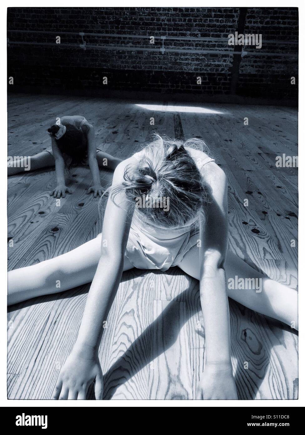 Little girls 8-10 years doing ballet stretching exercises on a wooden ...