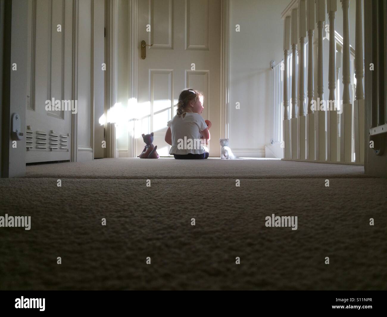Child on landing looking out of window Stock Photo - Alamy