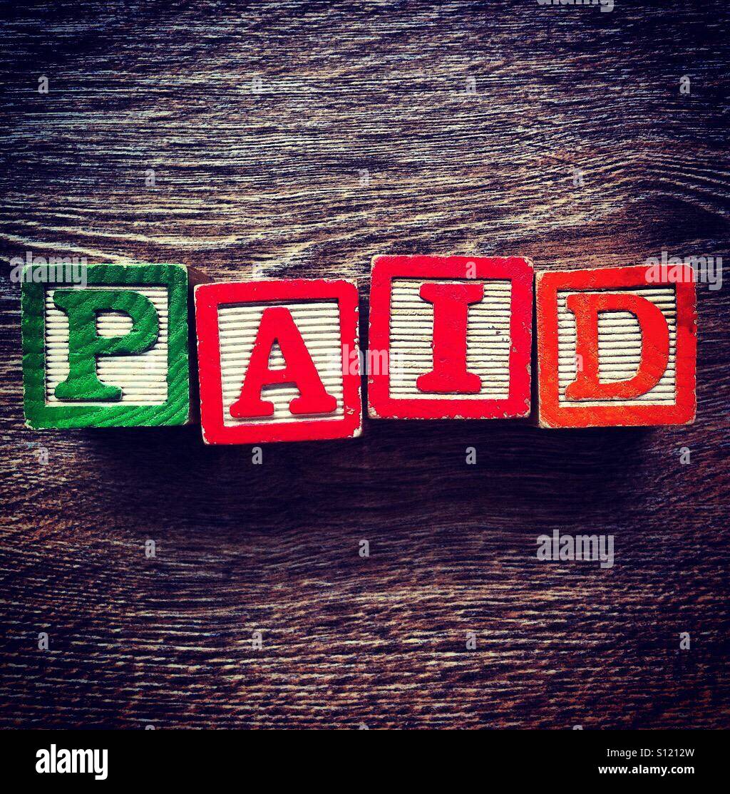 PAID word done with alphabet wood blocks letters Stock Photo - Alamy
