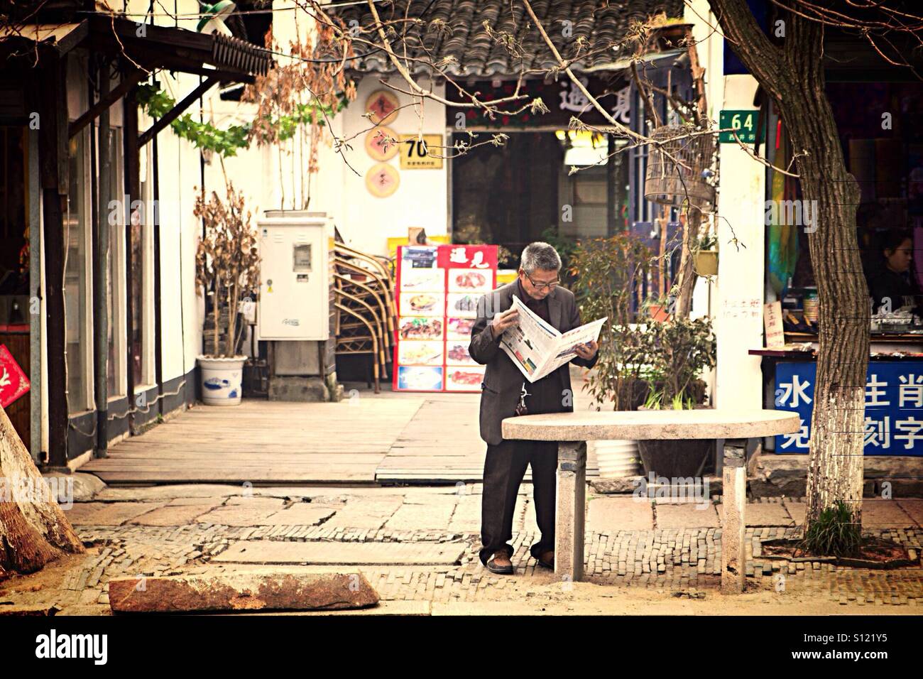 Chinese man reading news paper on the street Stock Photo - Alamy