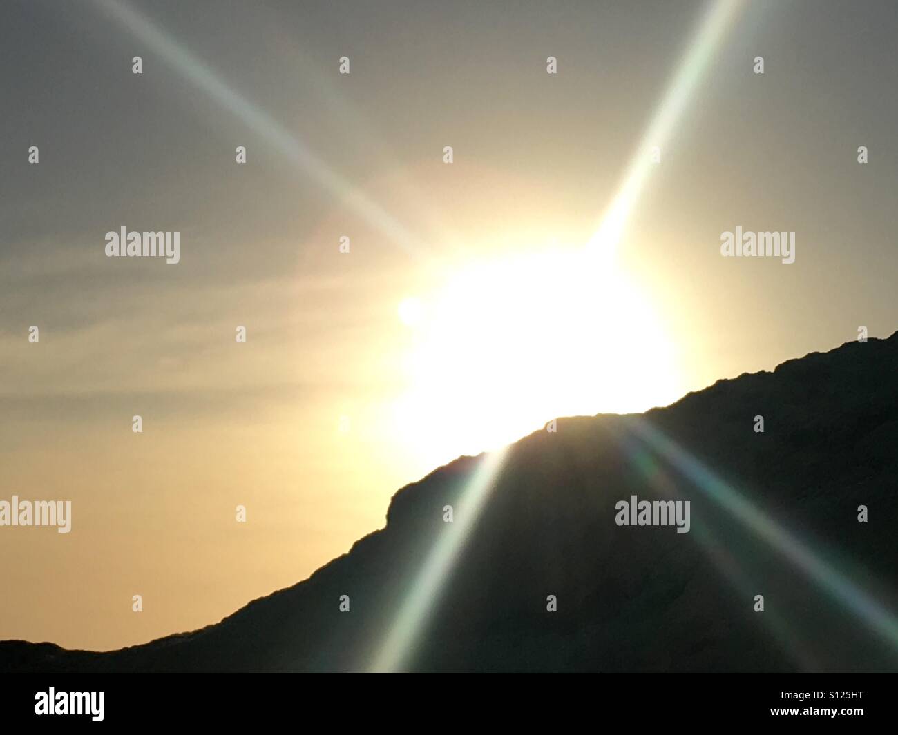 Sun shining over rock Stock Photo - Alamy