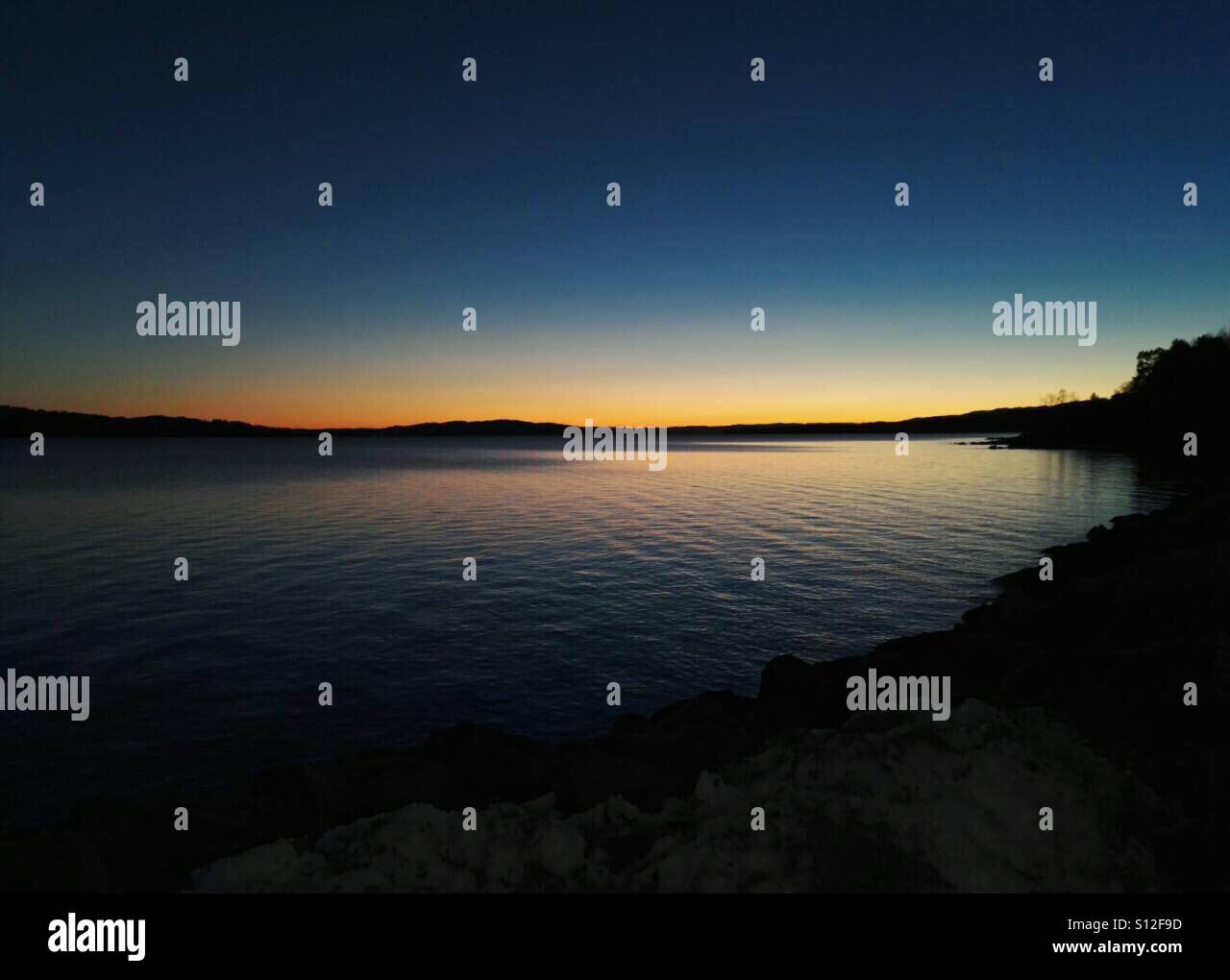 Sun setting in cold lake Stock Photo - Alamy