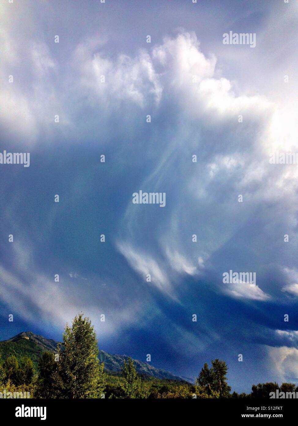 Storm cloud over trees and mountain Stock Photo - Alamy