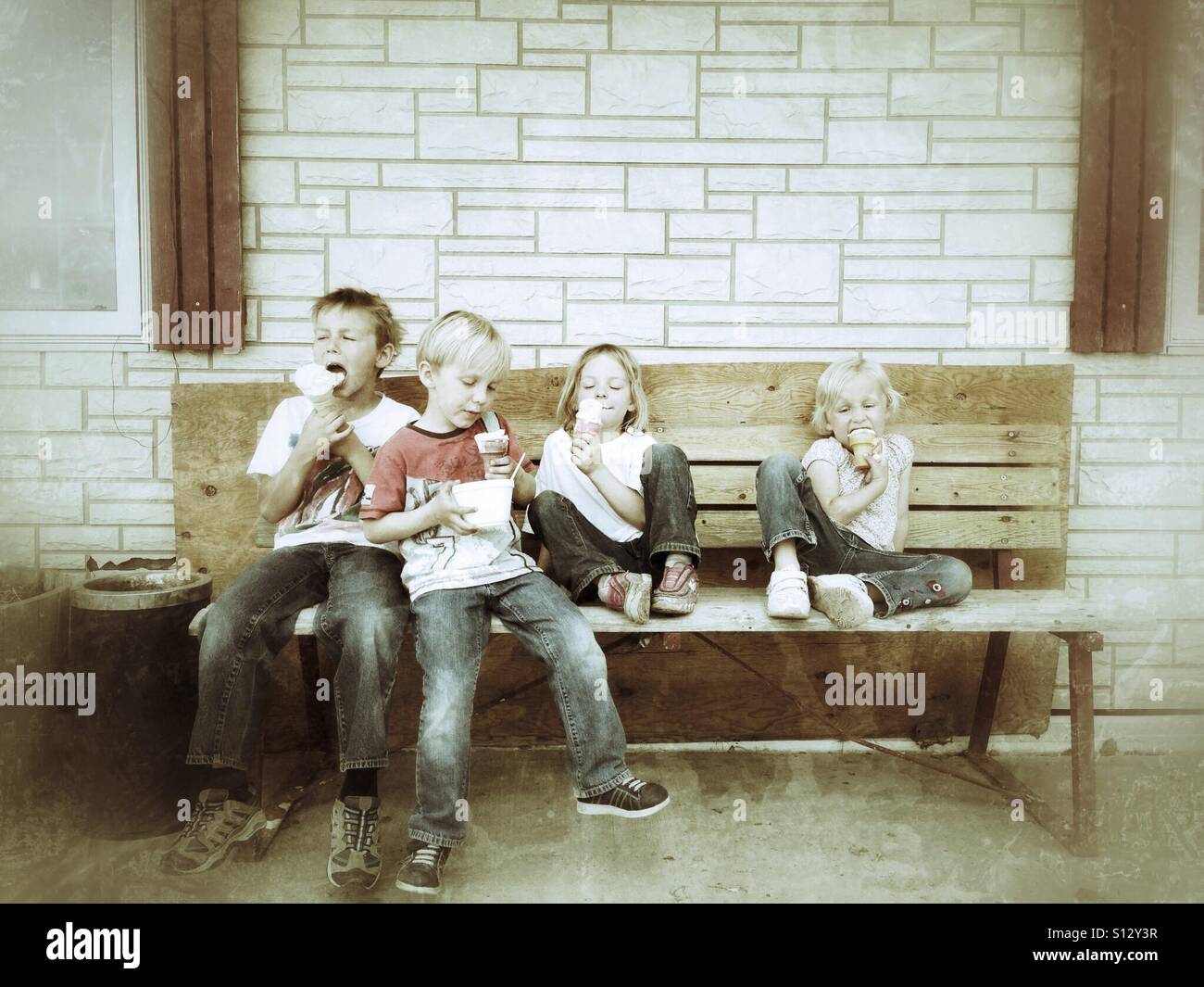 Four kids eating ice cream on a bench Stock Photo - Alamy