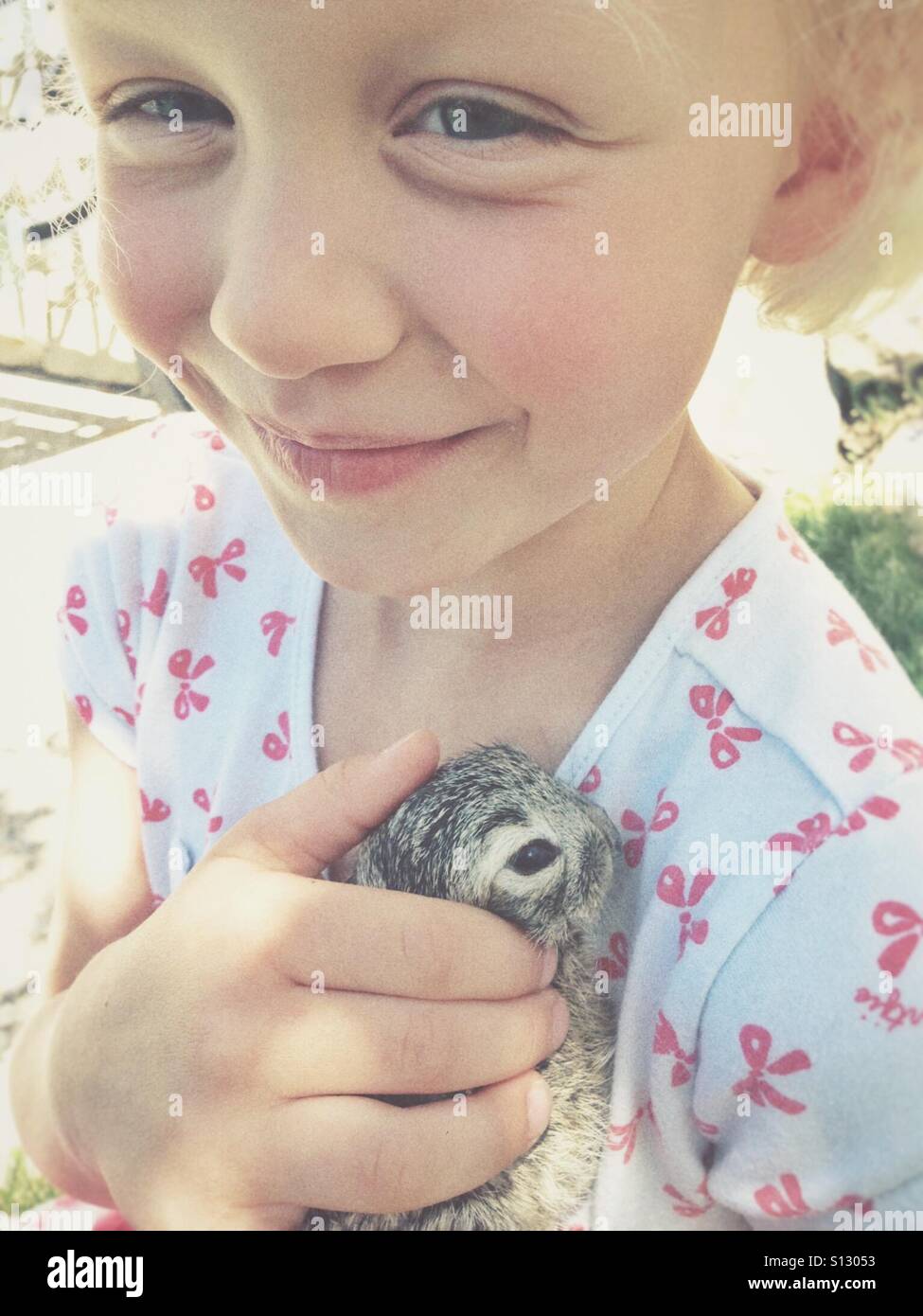 A young girl proudly protects the wild baby rabbit she rescued from a ...