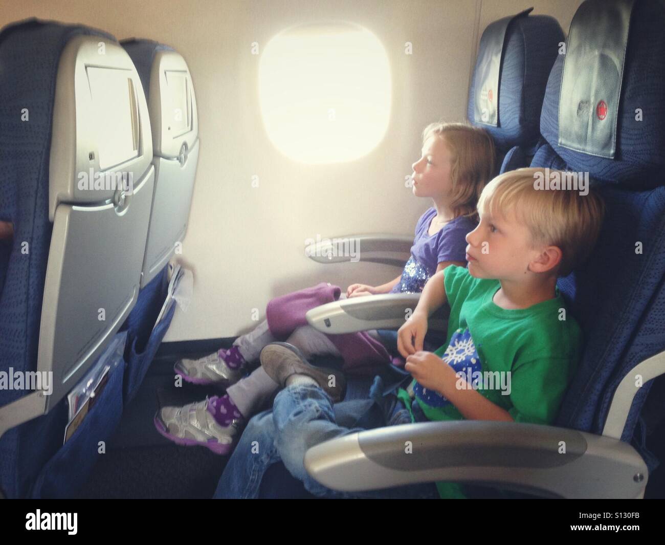 Two children on an airplane watch the in-flight entertainment Stock ...