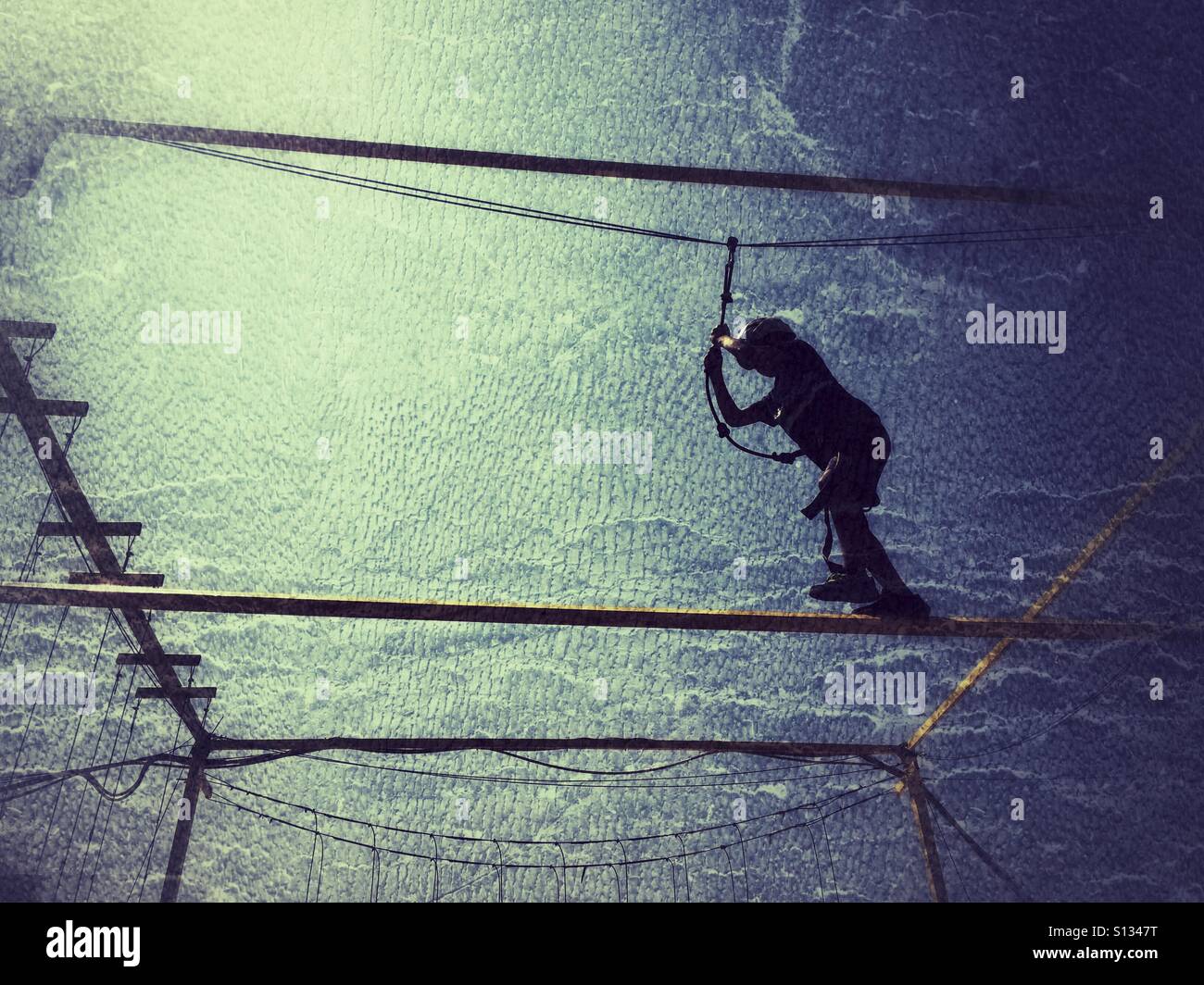 Boy sky walking while hanging from a rope Stock Photo - Alamy