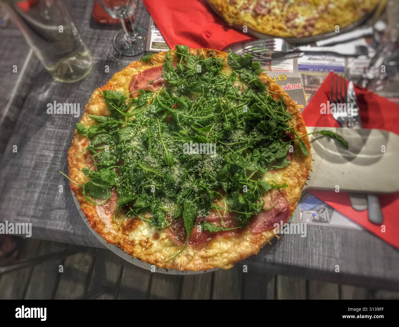 Pizza with salad rocket on the table in restaurant Stock Photo - Alamy
