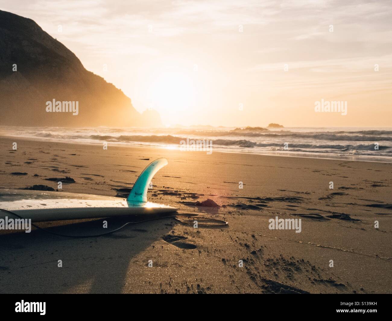 Surfboard on the beach under hot sun rays Stock Photo - Alamy