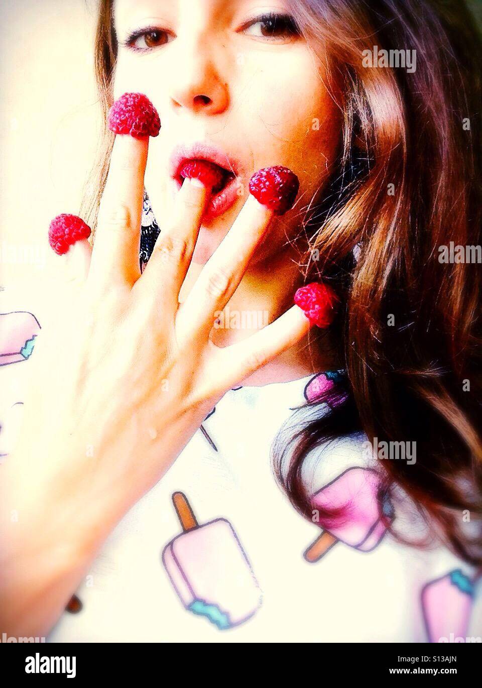 Girl eating raspberries from fingers Stock Photo - Alamy