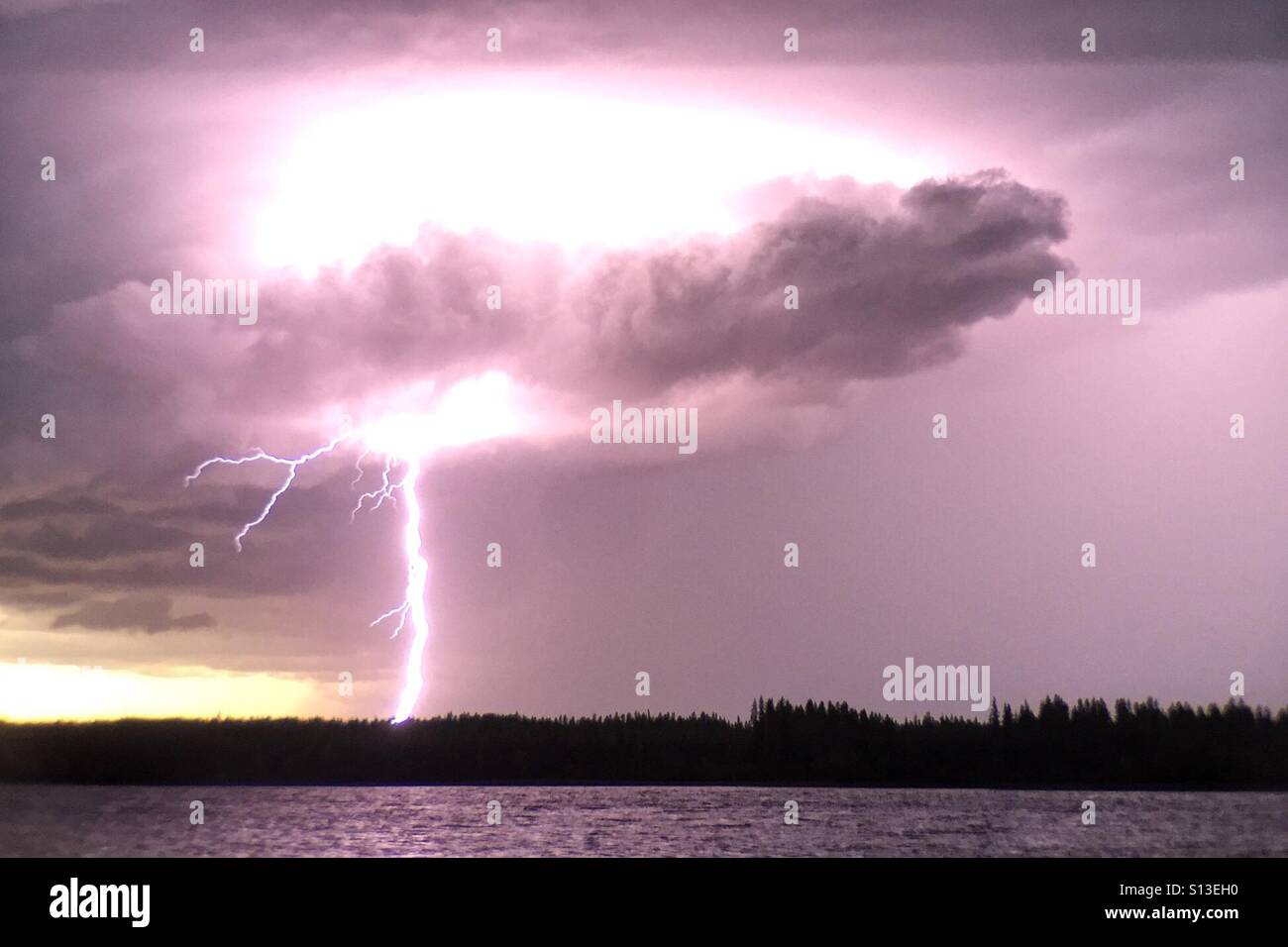 A lightning flash illuminates the sky above a storm cloud Stock Photo ...