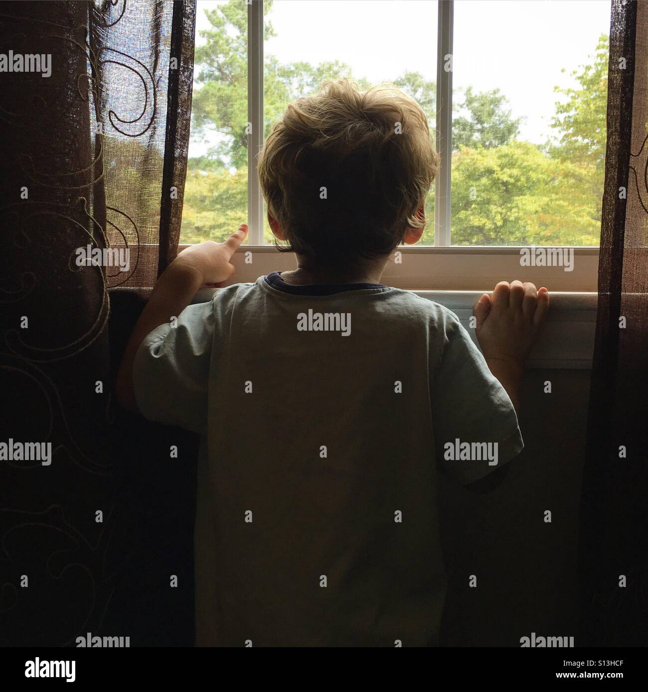 Little boy looking out window Stock Photo - Alamy