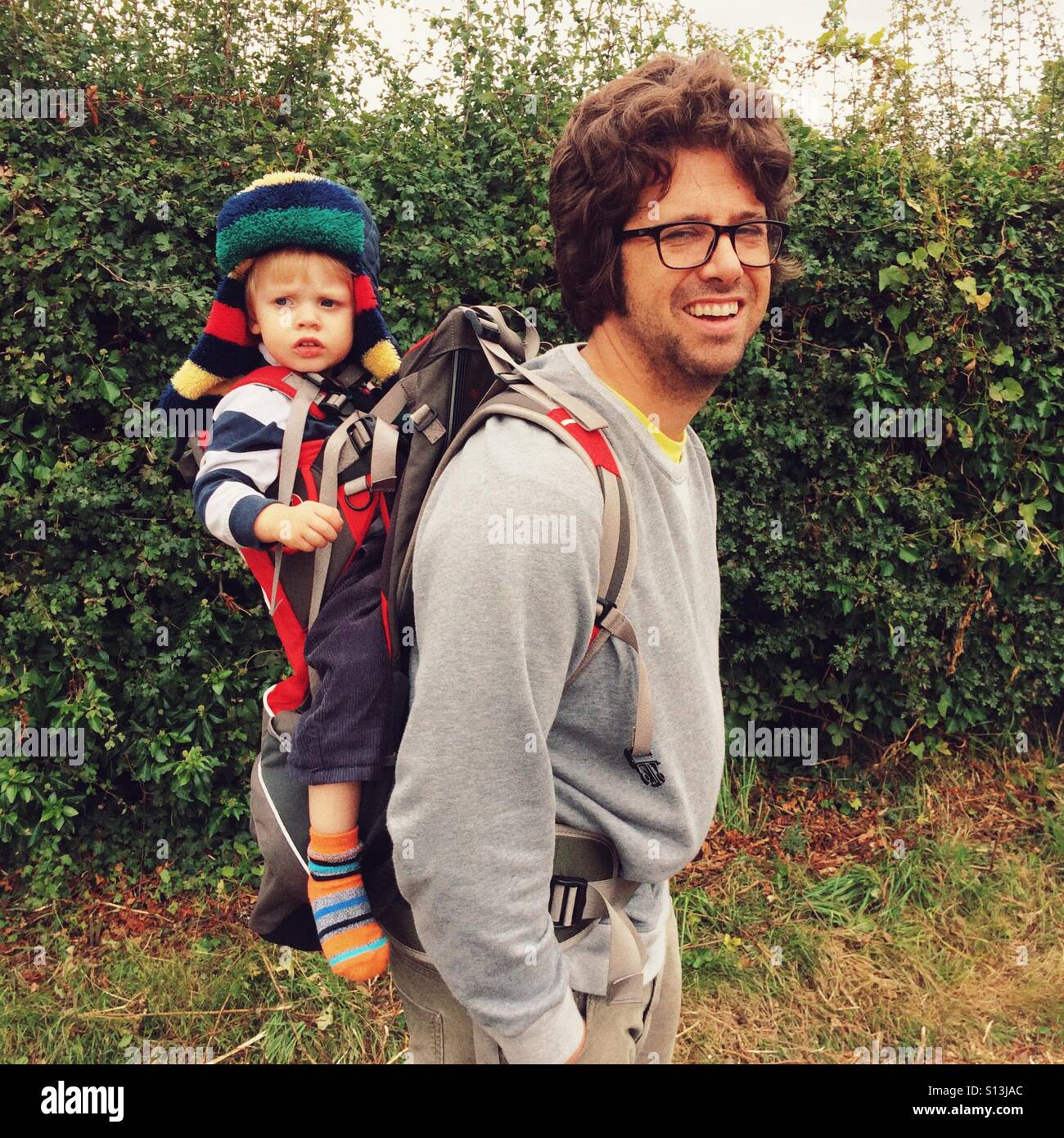 Man carrying a toddler in a rucksack style carrier Stock Photo - Alamy