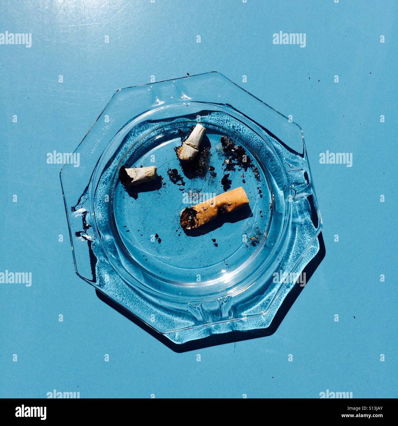 A used ashtray on a blue table Stock Photo - Alamy