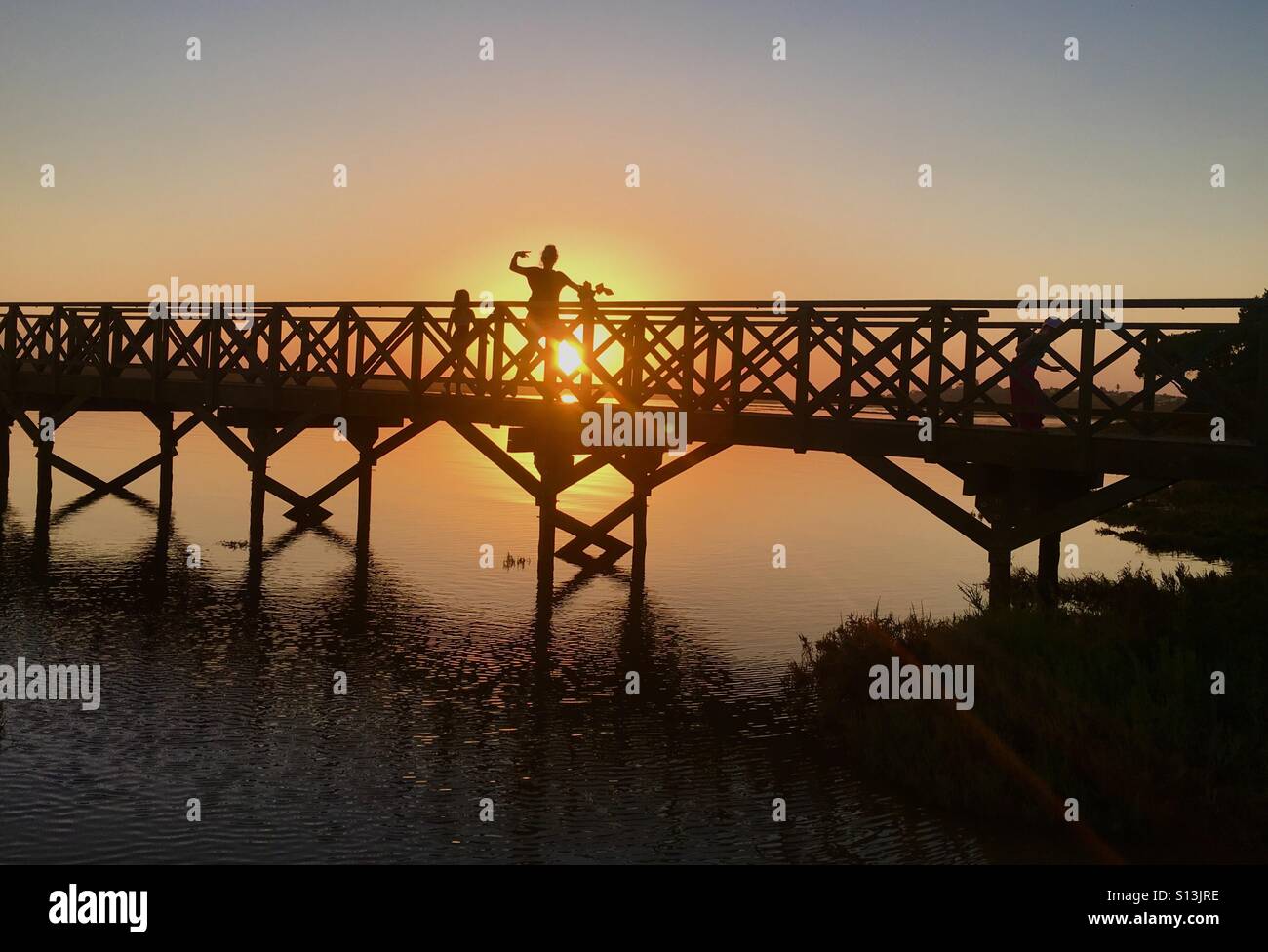 Sunset on the wooden bridge over the Ria Formosa nature reserve at ...