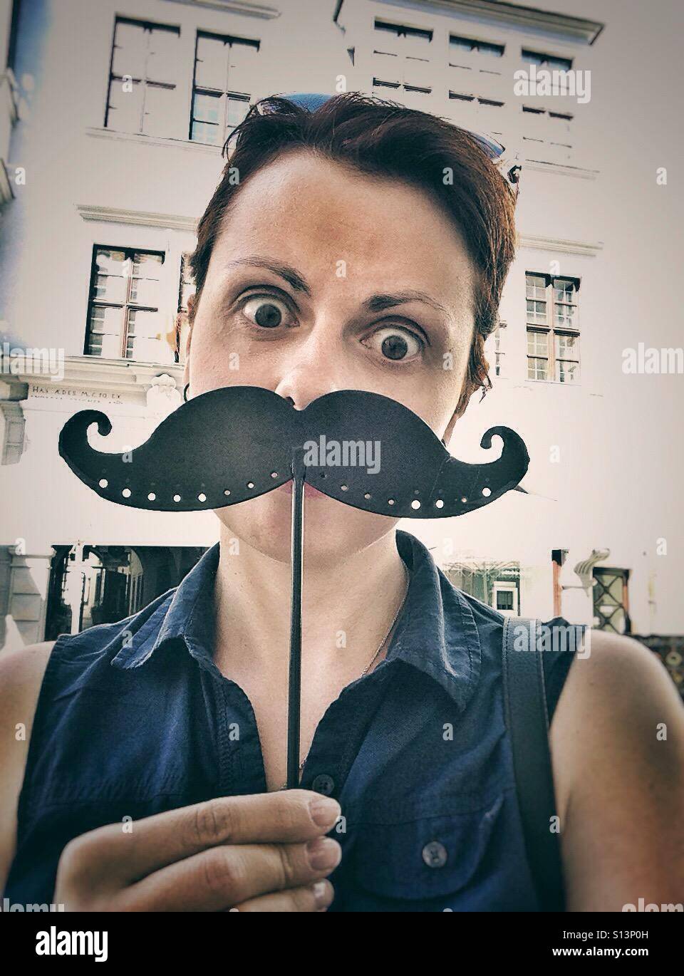 Girl having fun holding metal mustache on her face Stock Photo - Alamy
