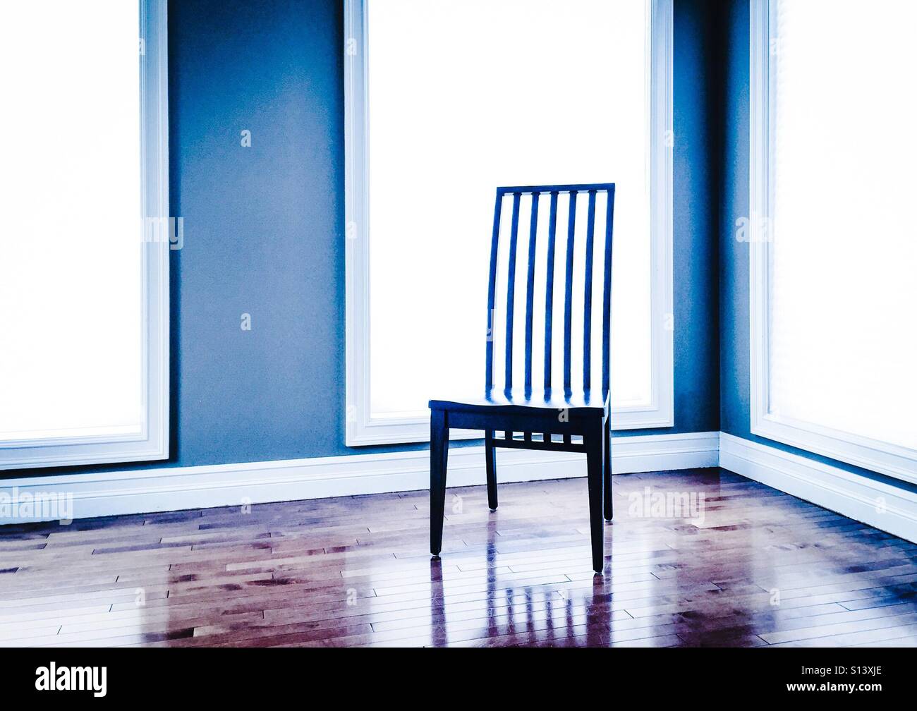A single chair in a room surrounded by large windows Stock Photo - Alamy