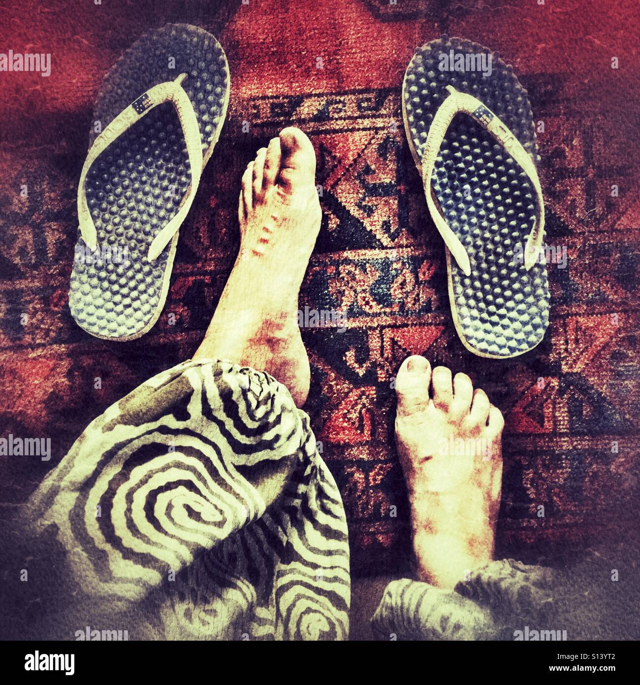 POV relaxing. Feet on rug, flip flops off Stock Photo - Alamy