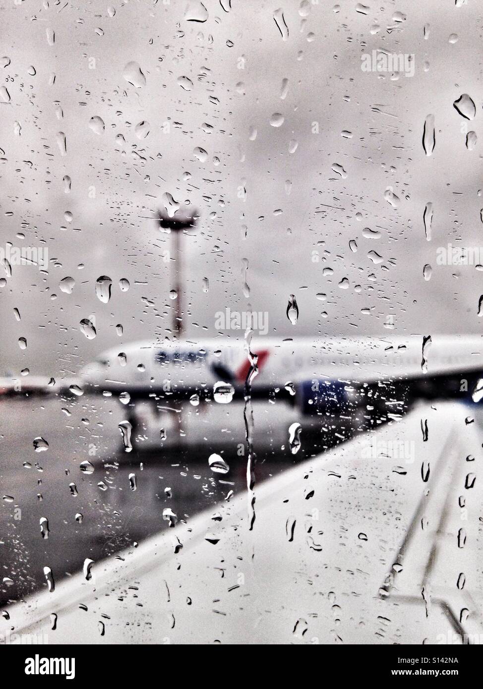 Defocused view on airplane through passenger window with rain drops ...
