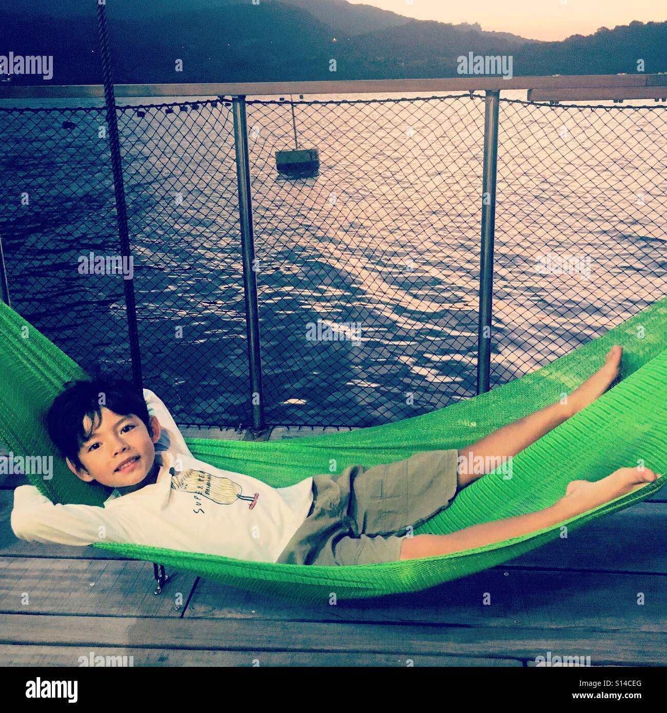 smiling boy on a hammock near the ocean Stock Photo - Alamy