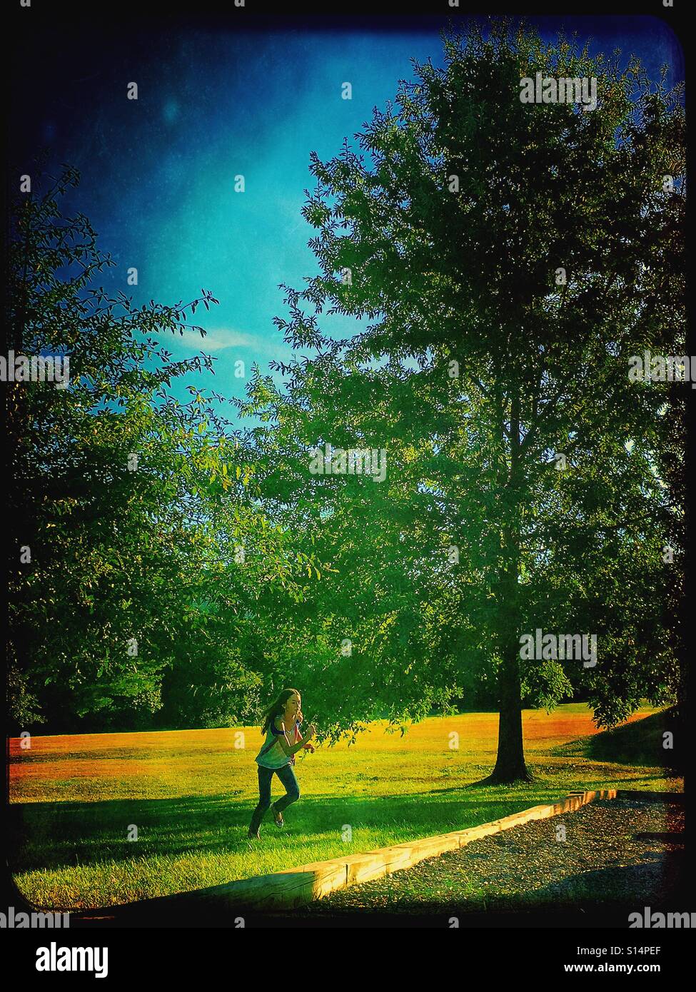 Girl running through park grass Stock Photo - Alamy