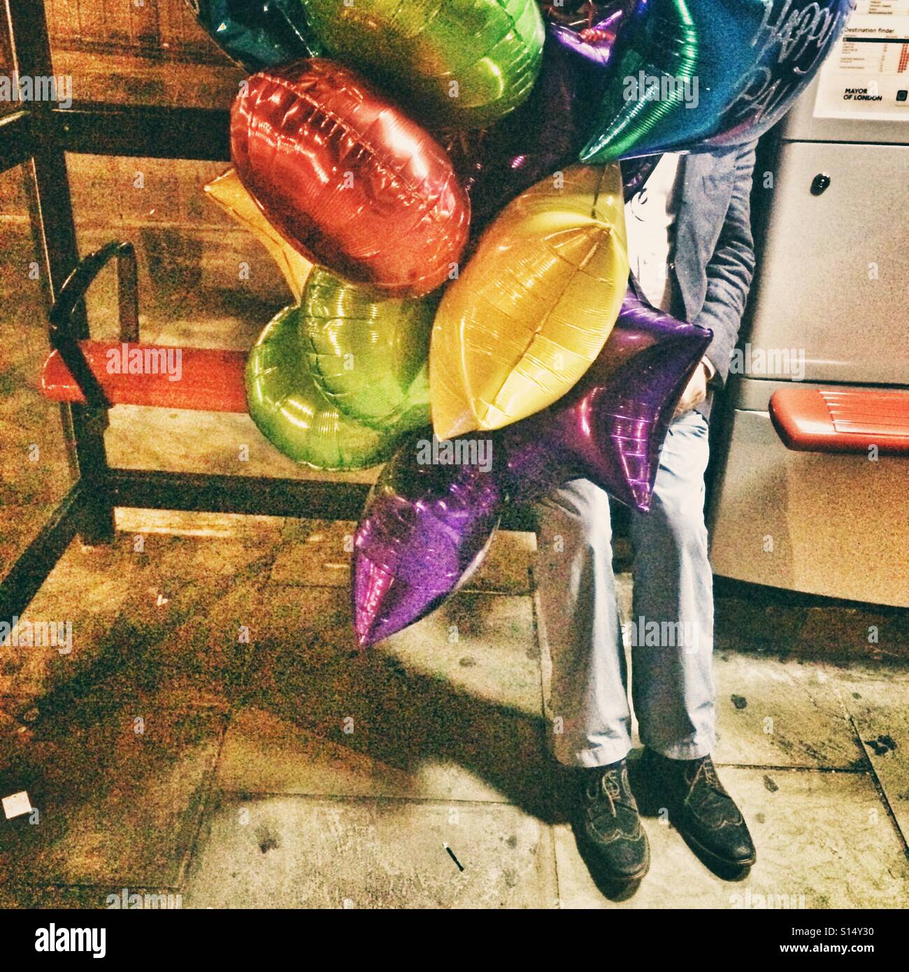 Man with party balloons at a bus stop Stock Photo - Alamy