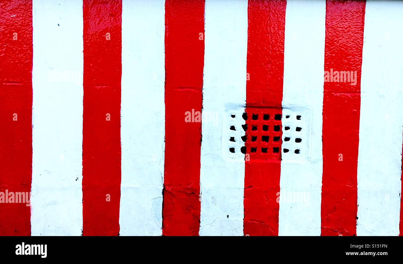 Red and white stripes painted on a wall with ventilation brick Stock ...