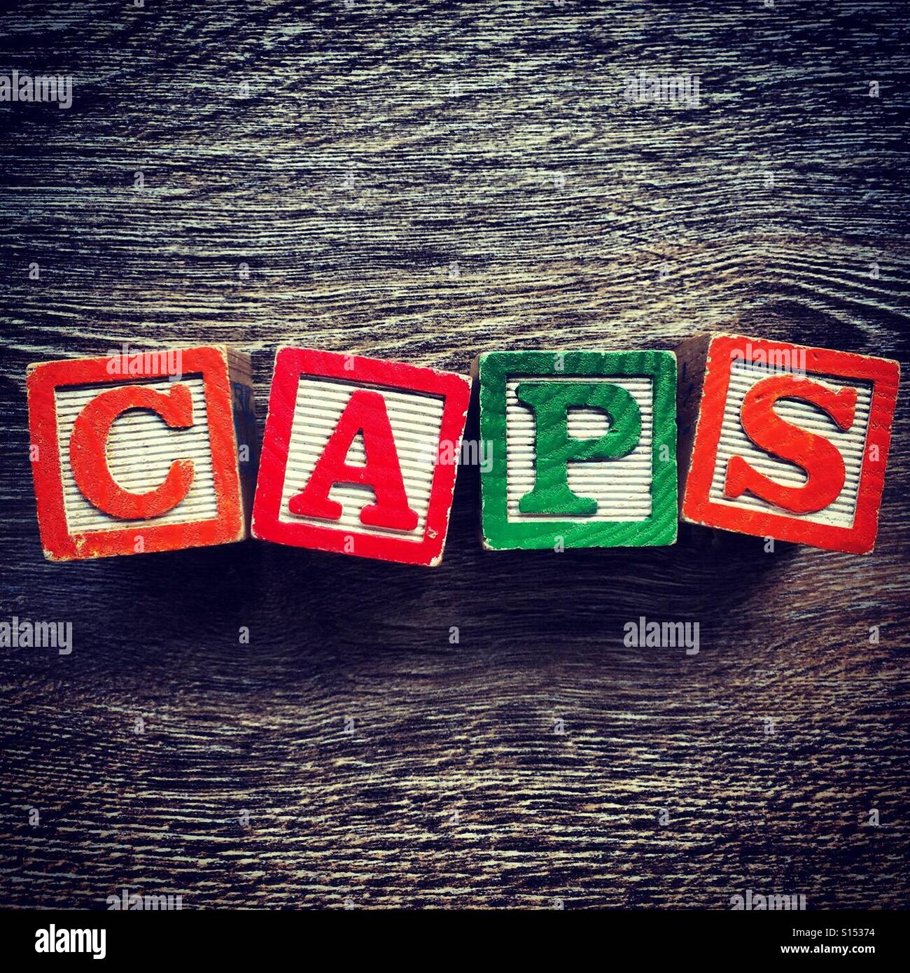CAPS word written with alphabet wood block letter toys Stock Photo - Alamy