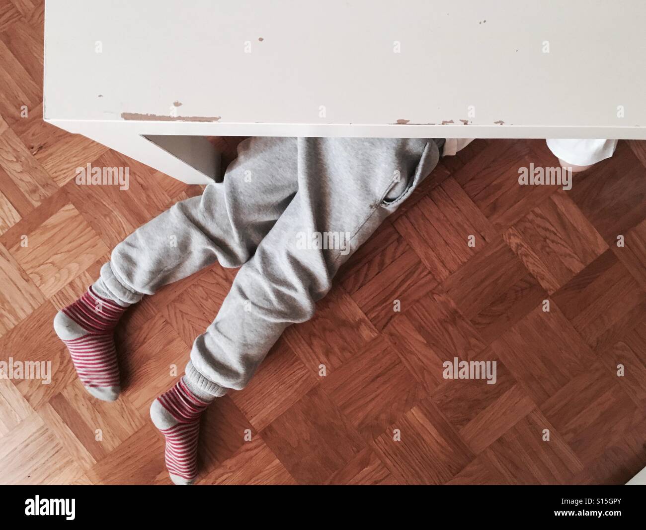 Little boy hiding beneath the table Stock Photo - Alamy