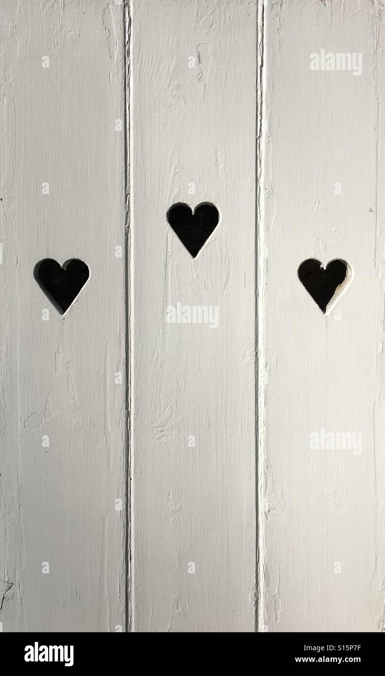 White window shutter with 3 heart-shaped cutouts in 3 wooden panels ...