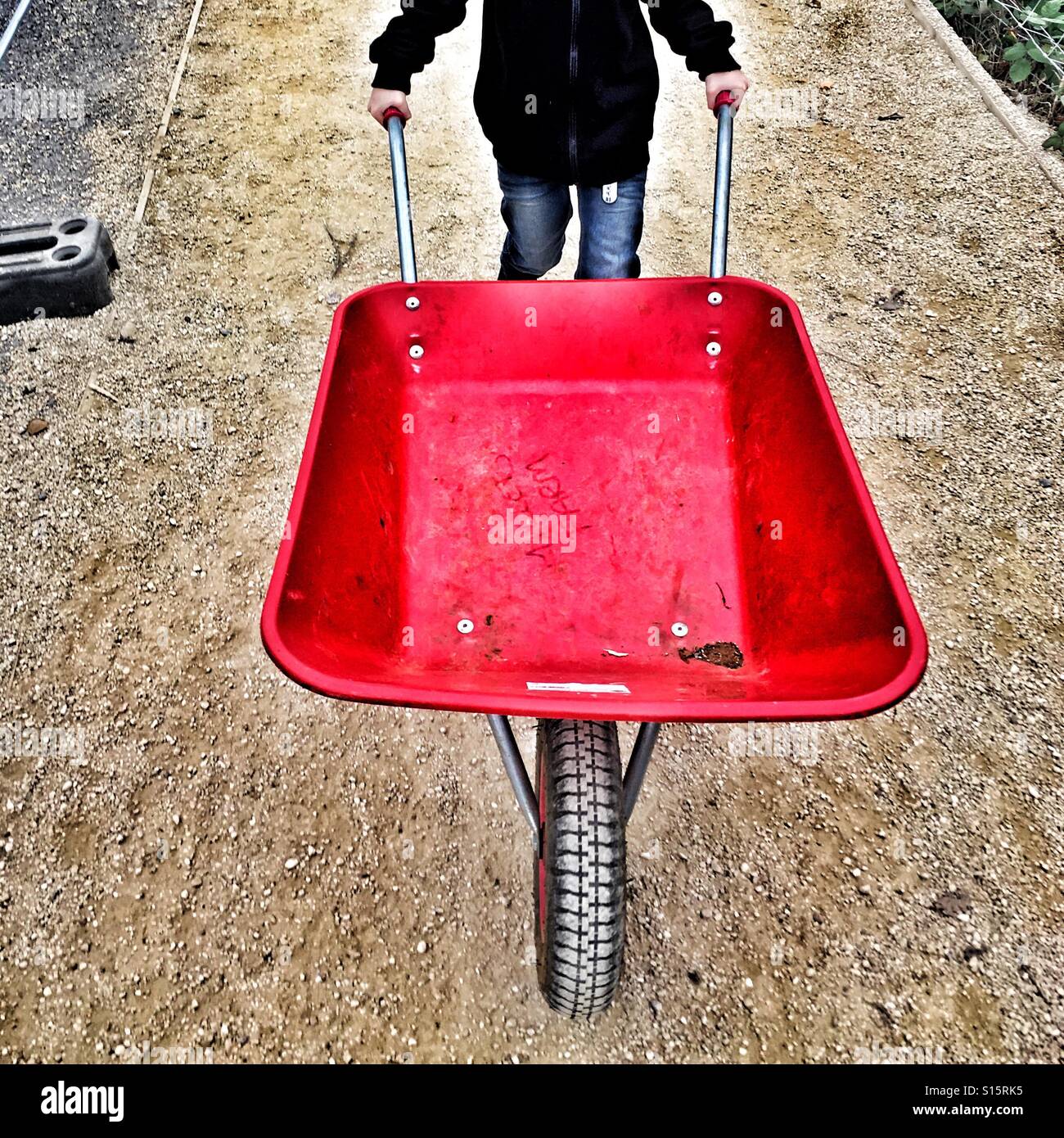 Pushing a bright red wheelbarrow Stock Photo - Alamy