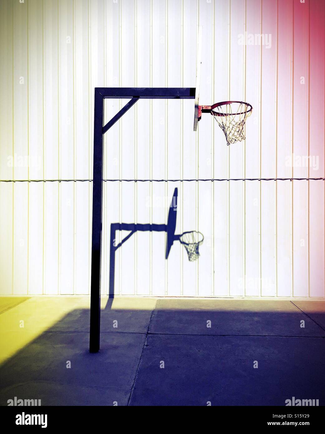 A basketball net and its shadow against a commercial building wall ...