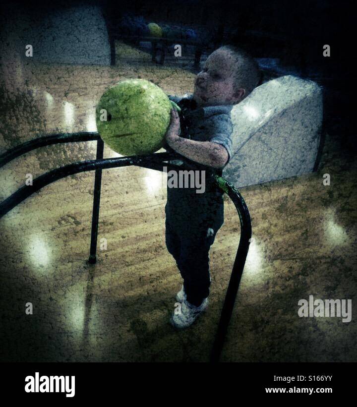 Young boy just about to push a bowling ball down the bowling alley ...