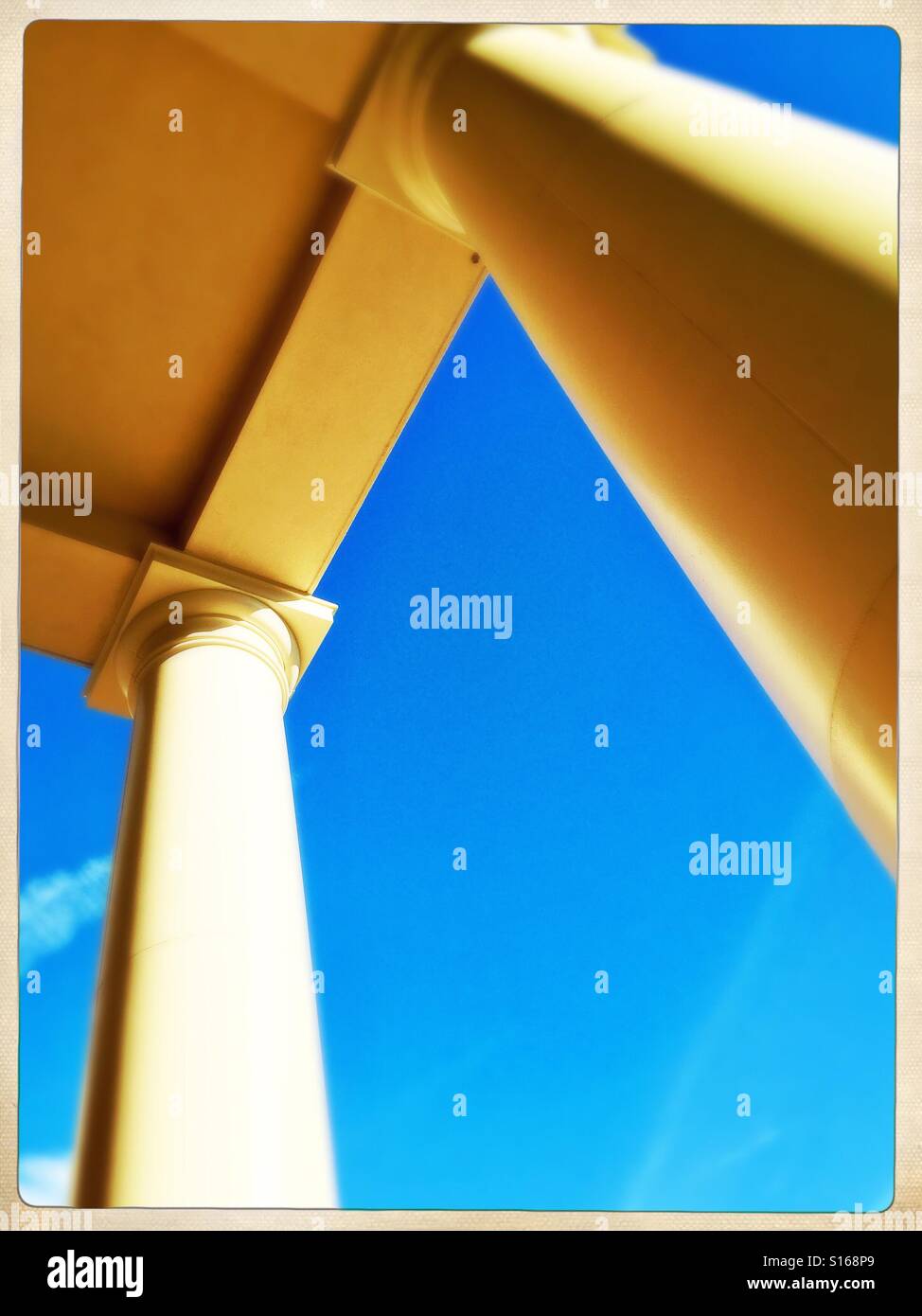 Two architectural columns support a high roof under a brilliant blue ...