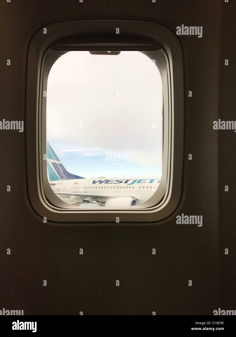 The view of a WestJet airplane through the window of another aircraft ...
