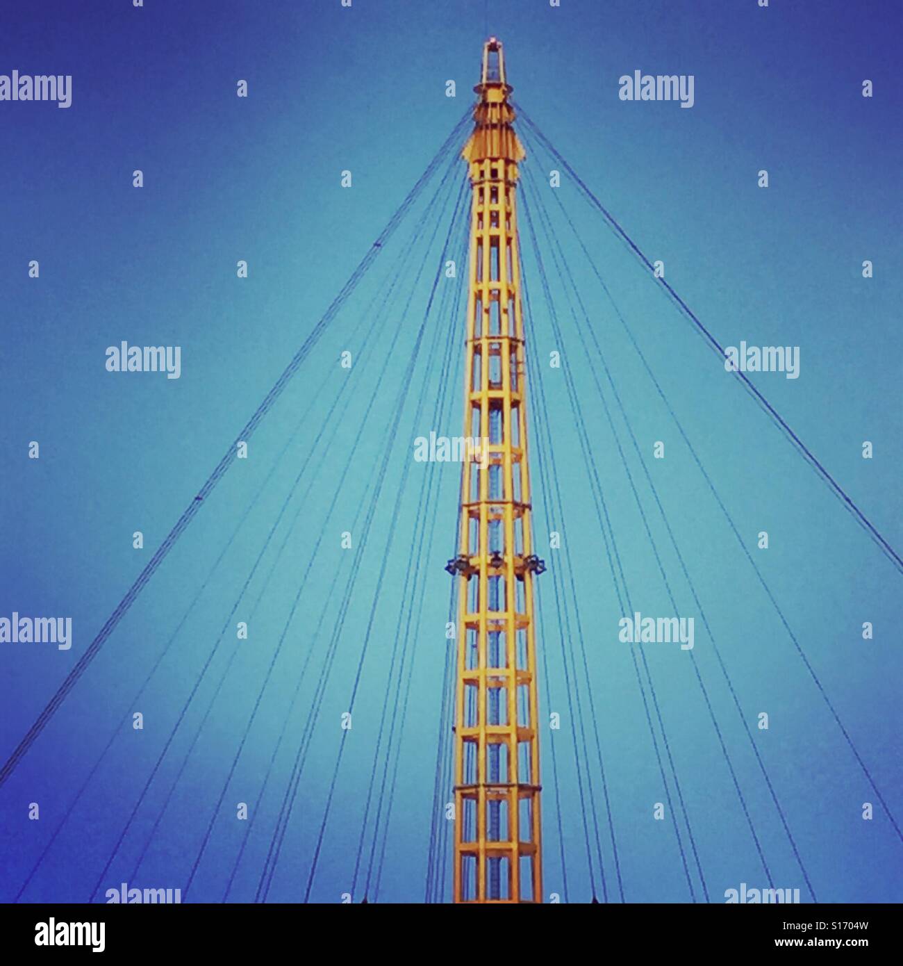 Yellow tower with support wires against blue sky Stock Photo - Alamy