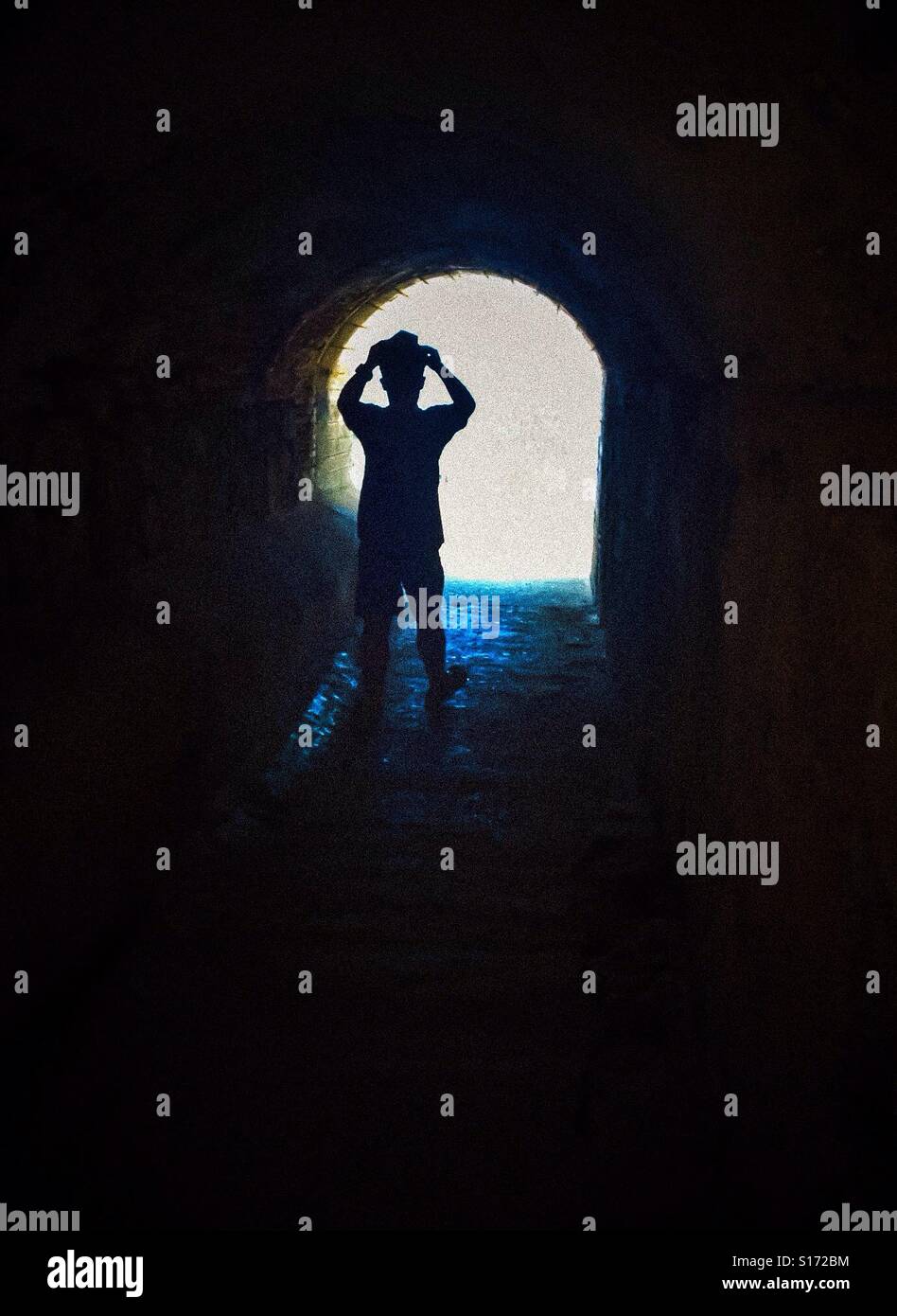 Silhouette of an anonymous perdon walking through a dark underpass ...