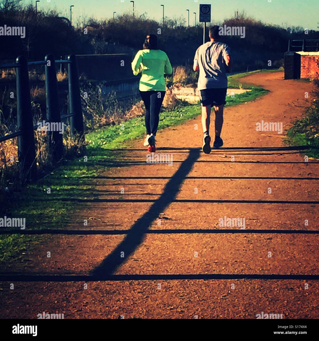 Two people jogging along a path alongside a canal Stock Photo - Alamy