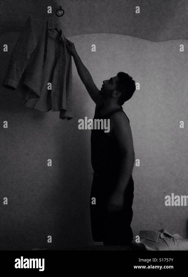Man reaching up for a hanging jacket Stock Photo - Alamy