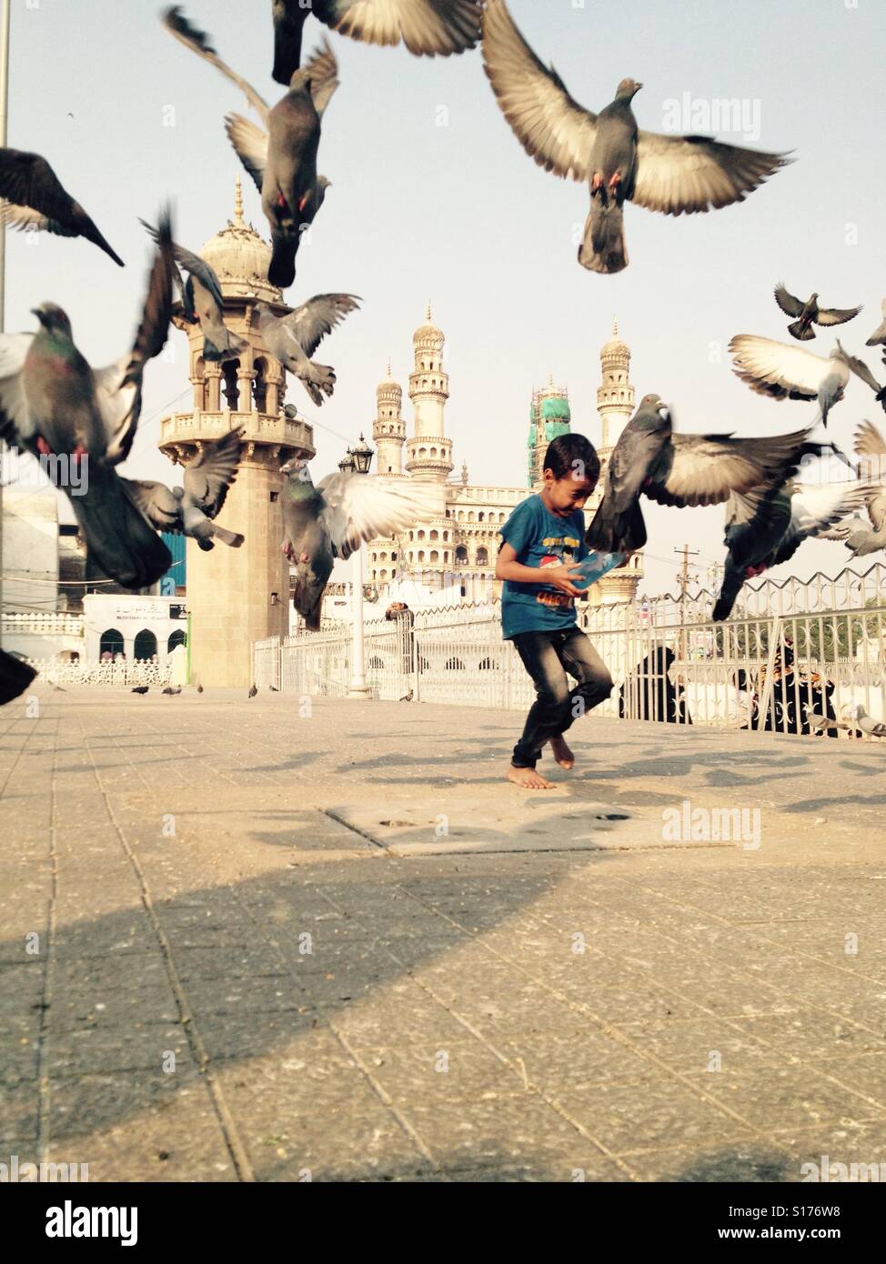 Little boy scaring away pigeons in front of a mosque Stock Photo - Alamy