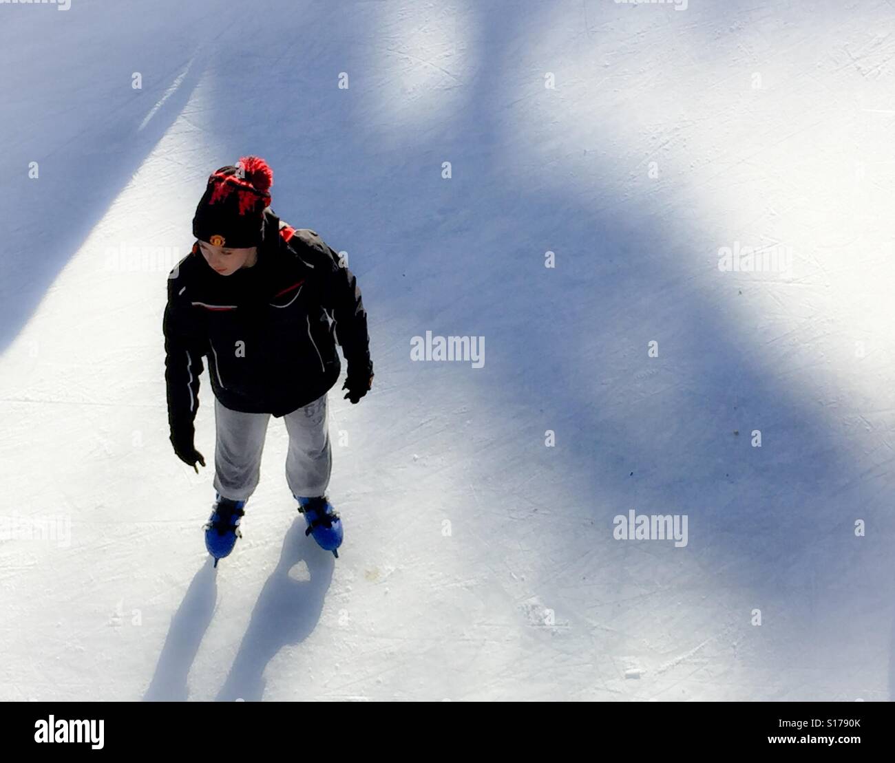 Boy ice skating with red hood Stock Photo - Alamy